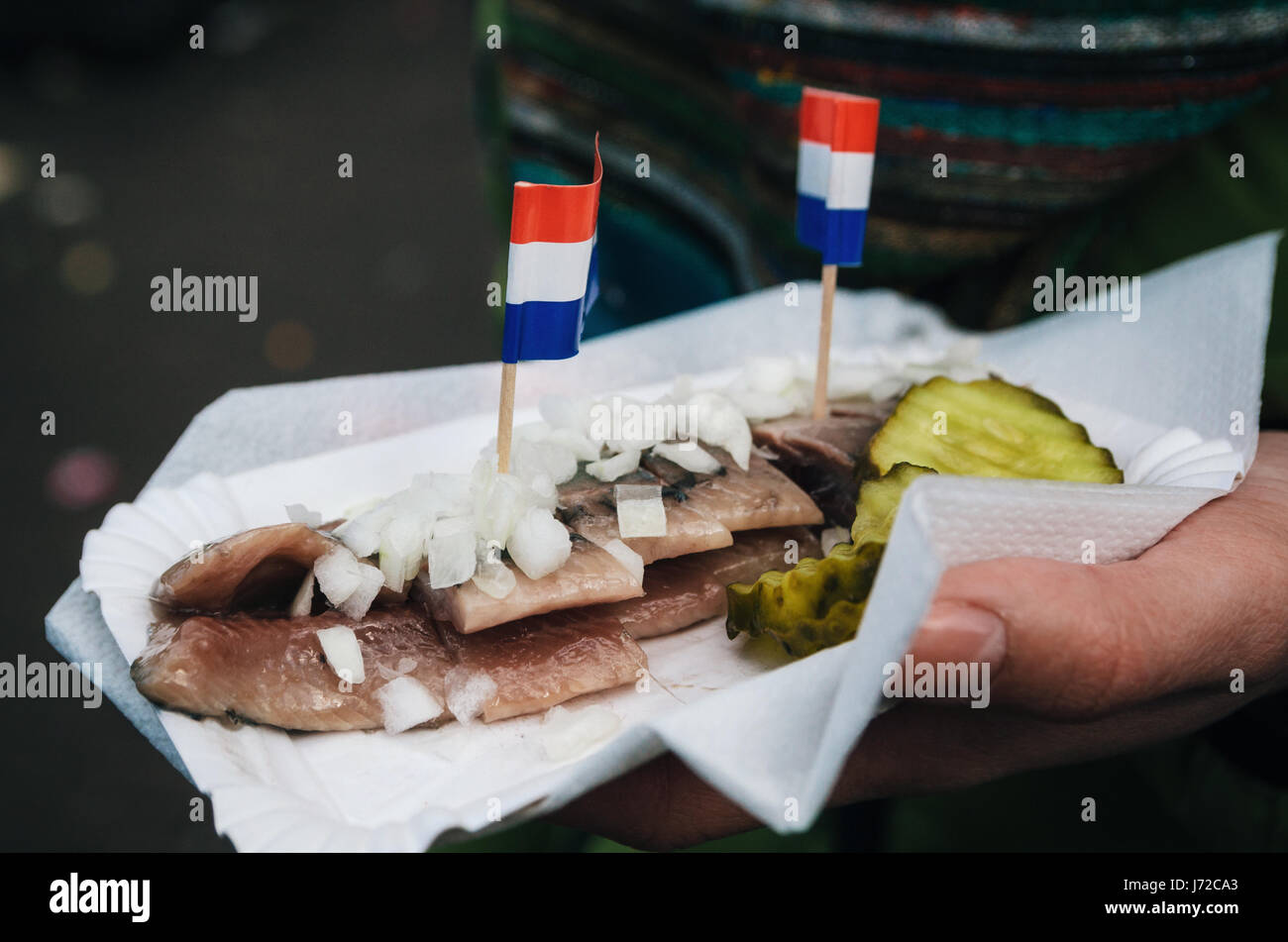 Eine Hand hält eine traditionelle holländische Delikatesse der Hering ...