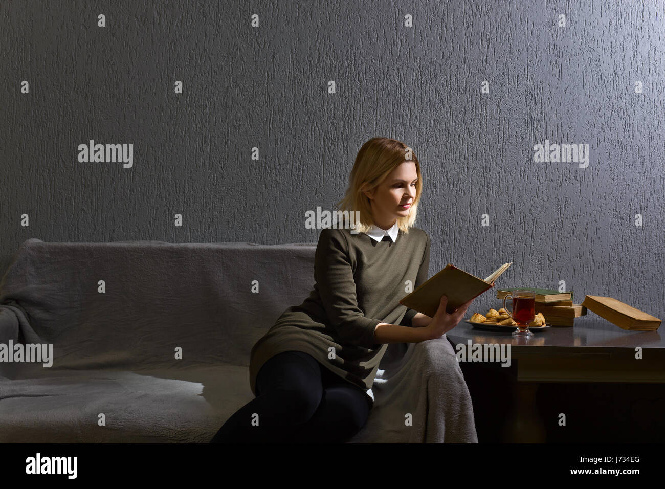 Junge Frau alte Lesebuch. Frau mit einem Buch auf der Couch in graues ...
