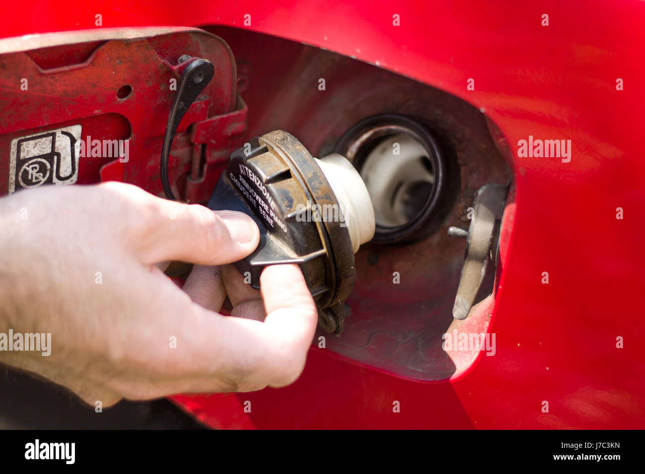 Der Mann schraubt den Tankdeckel im Auto. Eine männliche Hand öffnet ...