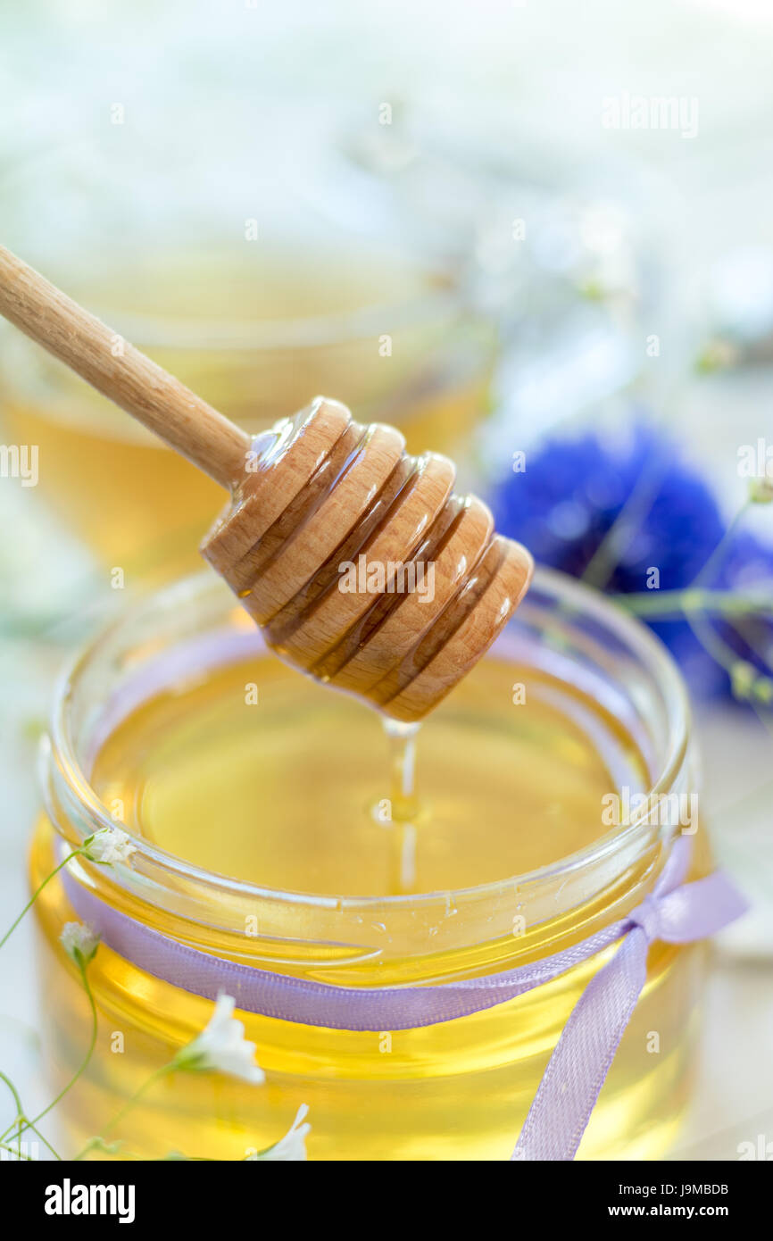 Honig in Gläsern und Tee mit weißen Frühlingsblumen und Kornblume auf ...