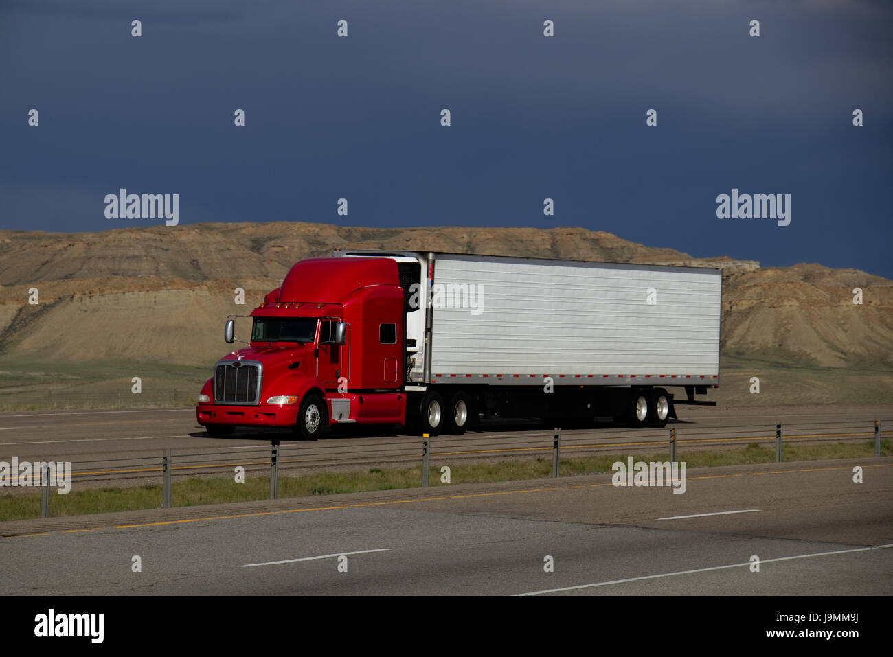 Ein rot Peterbilt Semi Truck zieht einem weißen Anhänger entlang einer ...