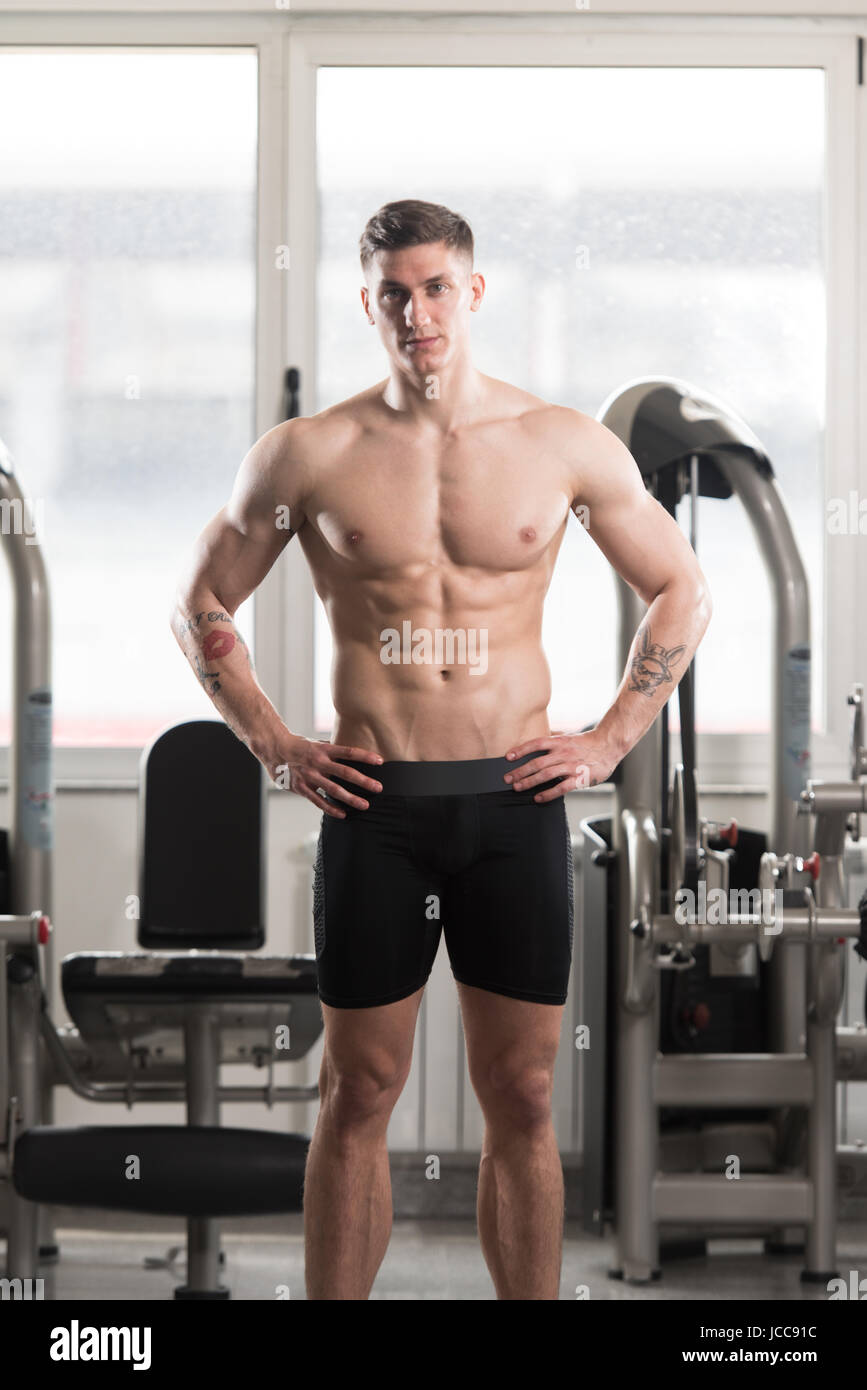Hübscher junger Mann standhaft In der Turnhalle und biegen Muskeln ...
