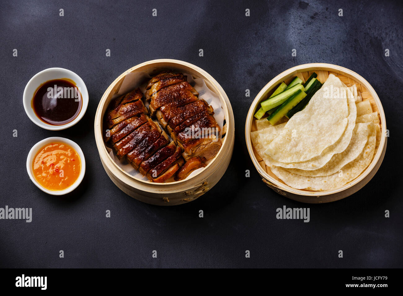 Peking-Ente in Bambus Dampfgarer serviert mit frischer Gurke, Sauce und ...