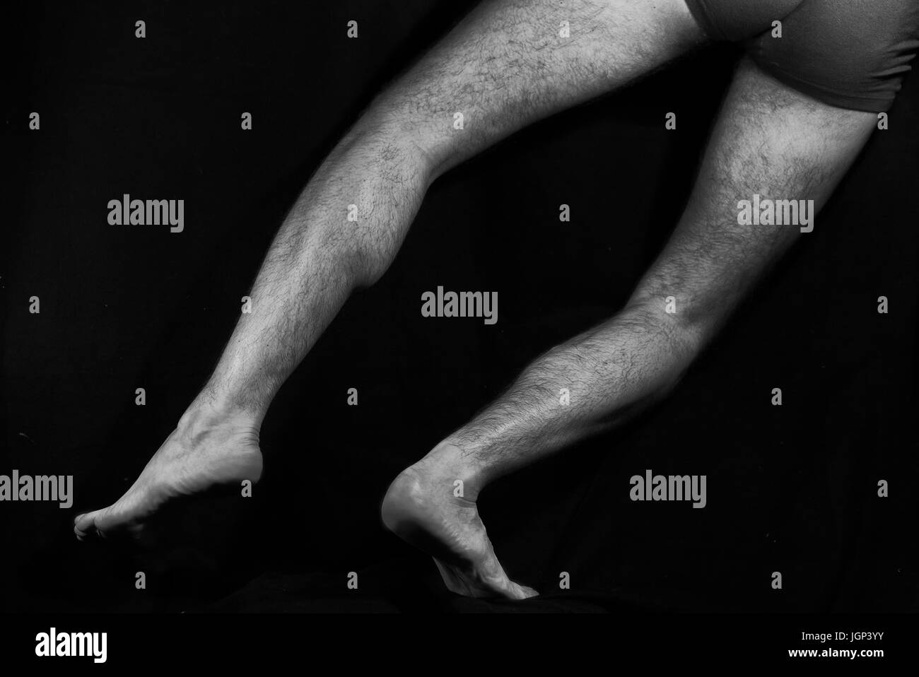Schön, muskulös, Nackte männliche Füße auf einem schwarzen Hintergrund ...