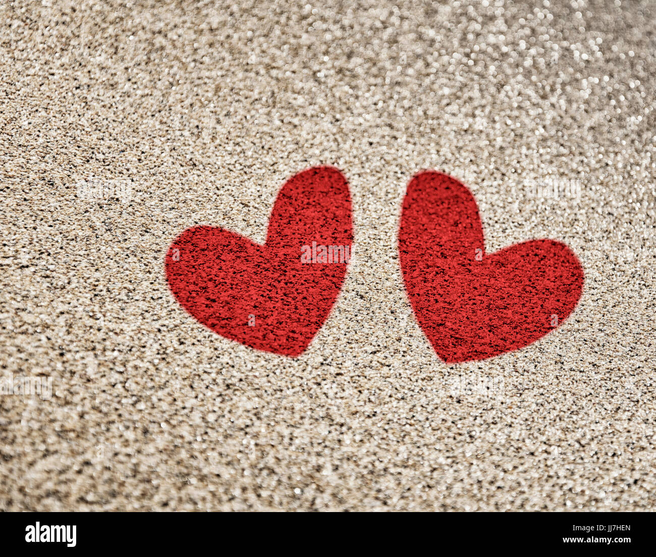 Zwei rote Herzen auf dem Sand, ein Symbol der Liebe gemalt ...