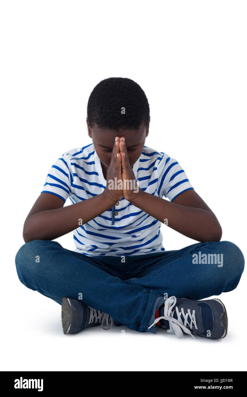Junge am Boden sitzen und beten vor weißem Hintergrund Stockfotografie ...