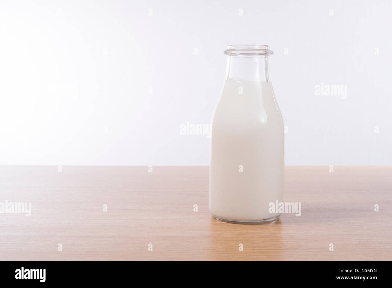 Eine Flasche frische Kuhmilch auf der Spitze eines einfachen Holz ...