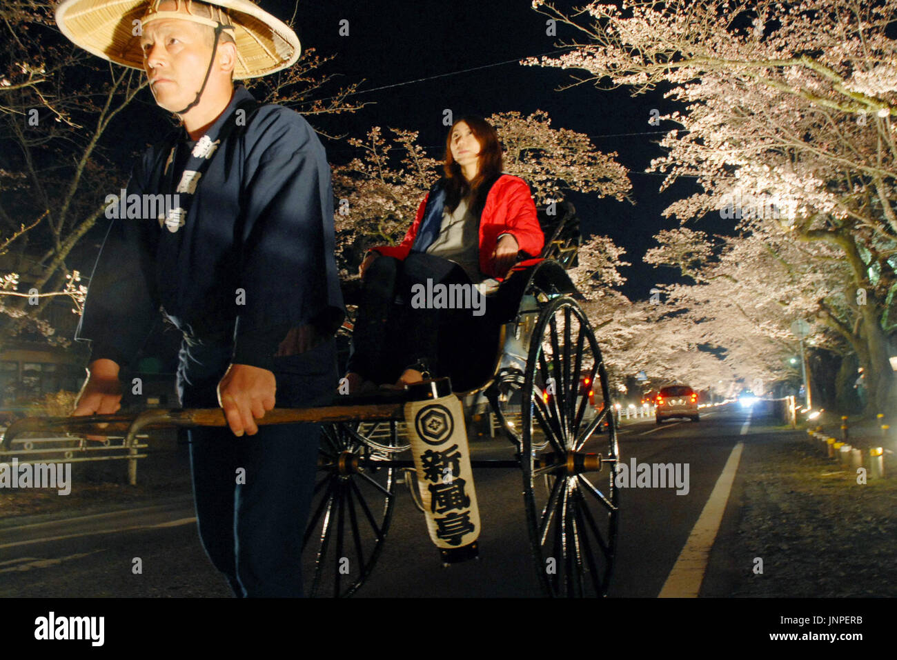 TOMIOKA, Japan - Landwirt Ryoichi Endo (L) zieht eine Rikscha tragen eine Frau durch einen ...