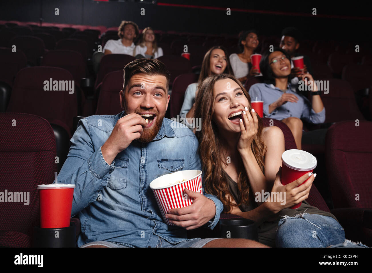 Glückliches Paar Popcorn essen und Lachen beim Sitzen und beobachten Film im Kino ...