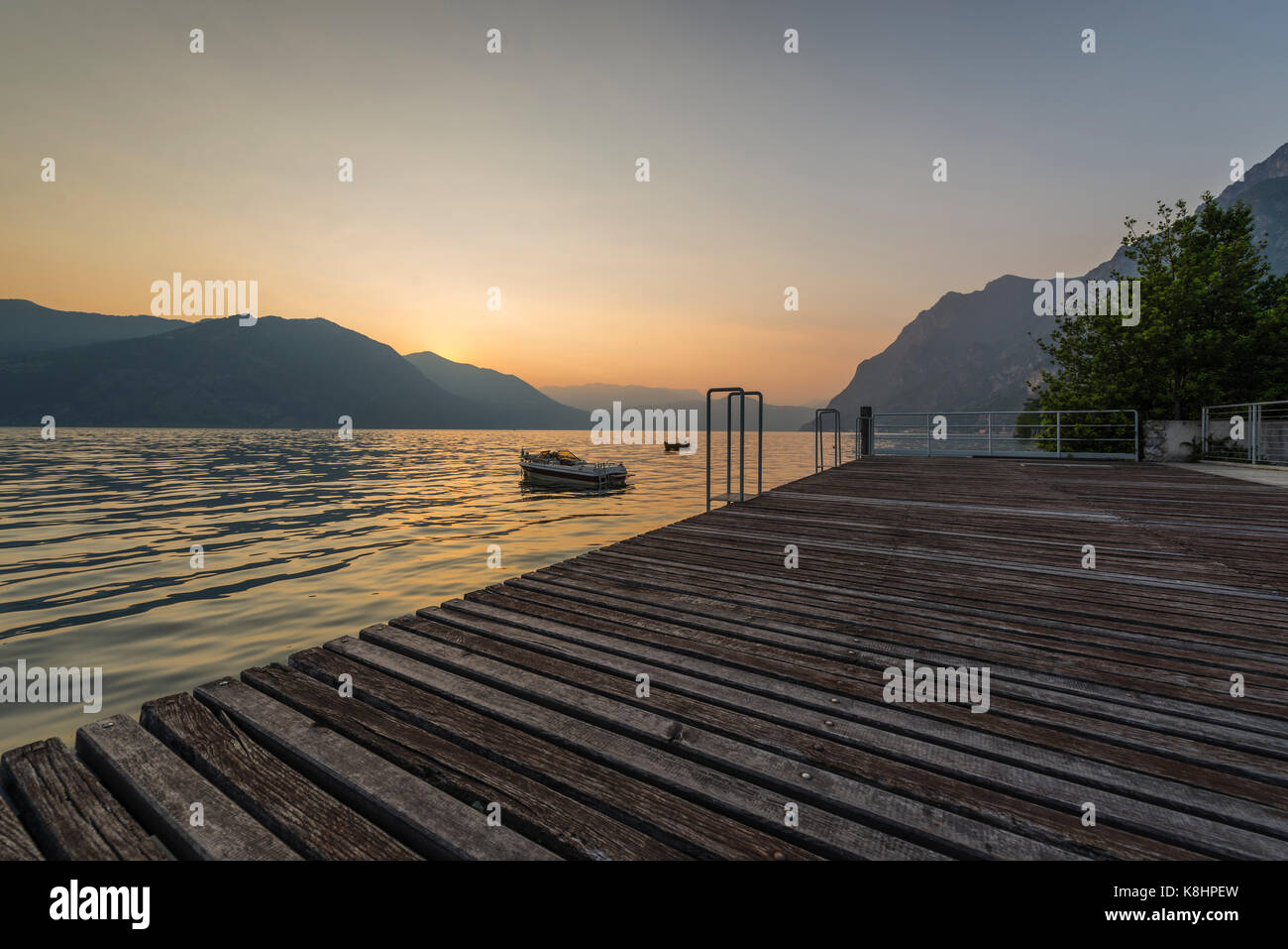 Steg mit Holzbohlen und Boot auf See in den Sonnenuntergang über den ...