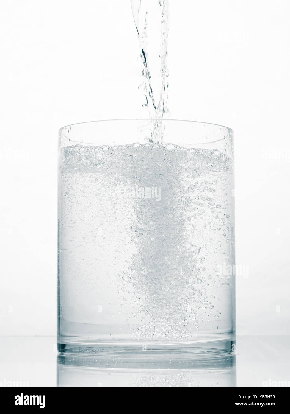 Das Gießen von Wasser im Glas auf weißem Hintergrund Stockfotografie ...