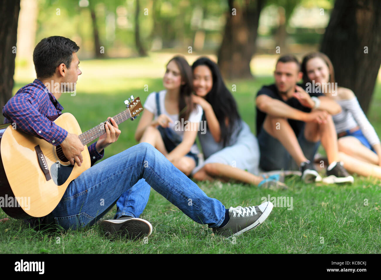 Mann singen Song mit Gitarre zu seinen Freunden im Park auf warmen ...