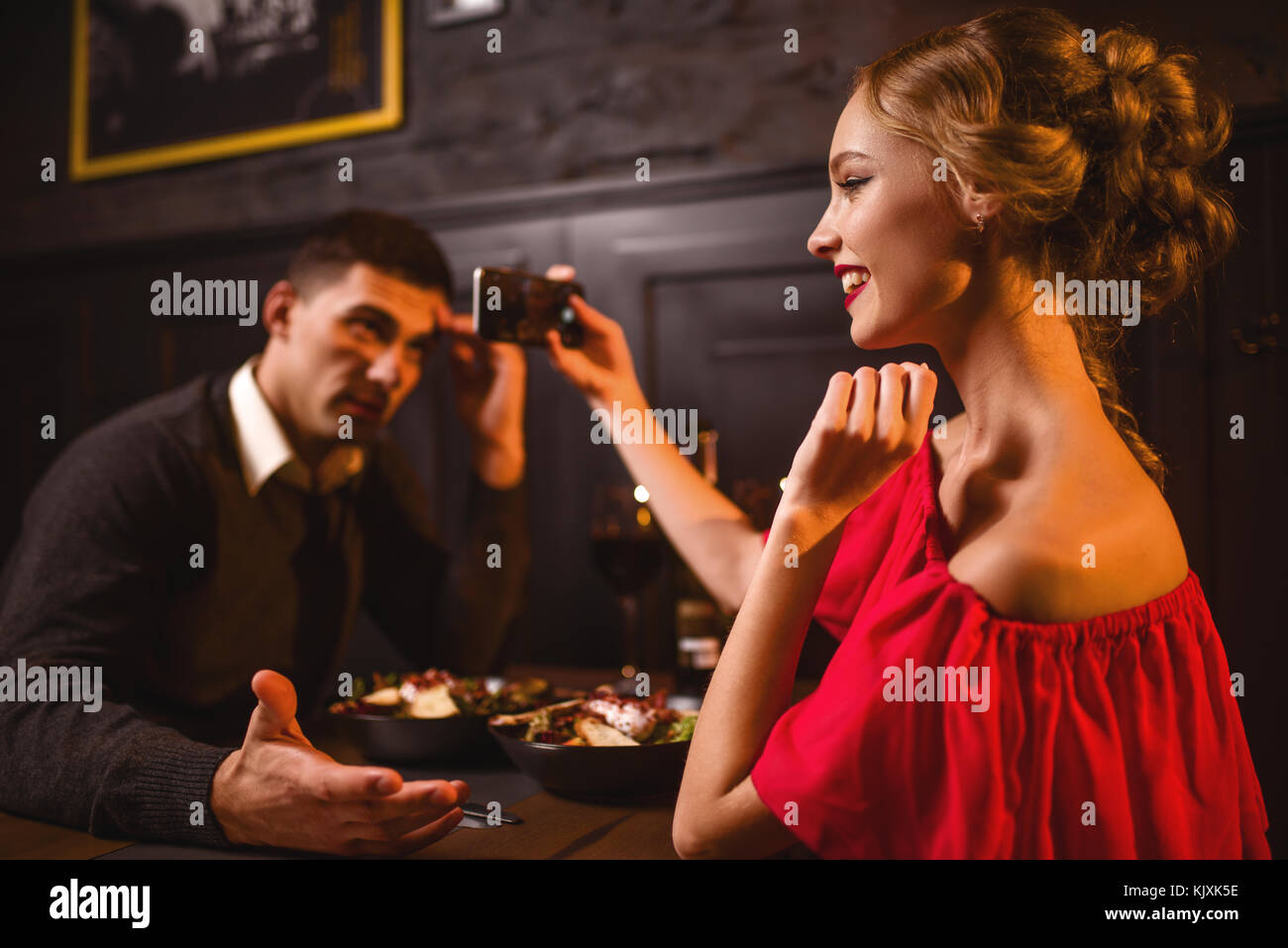 Lächelnde Frau im roten Kleid macht Bild von ihr Mann am Telefon Kamera ...