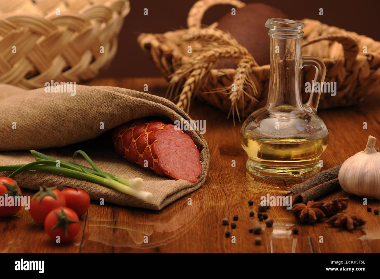 Wurst und Brot in einem Weidenkorb und Gemüse und Knoblauch auf einem ...