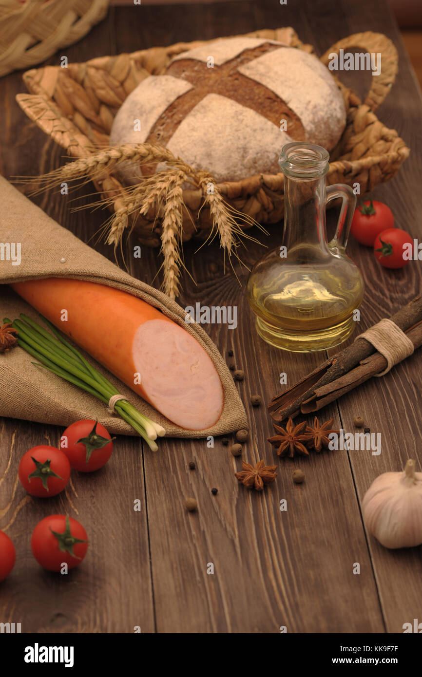 Wurst und Brot in einem Weidenkorb und Gemüse und Knoblauch auf einem ...