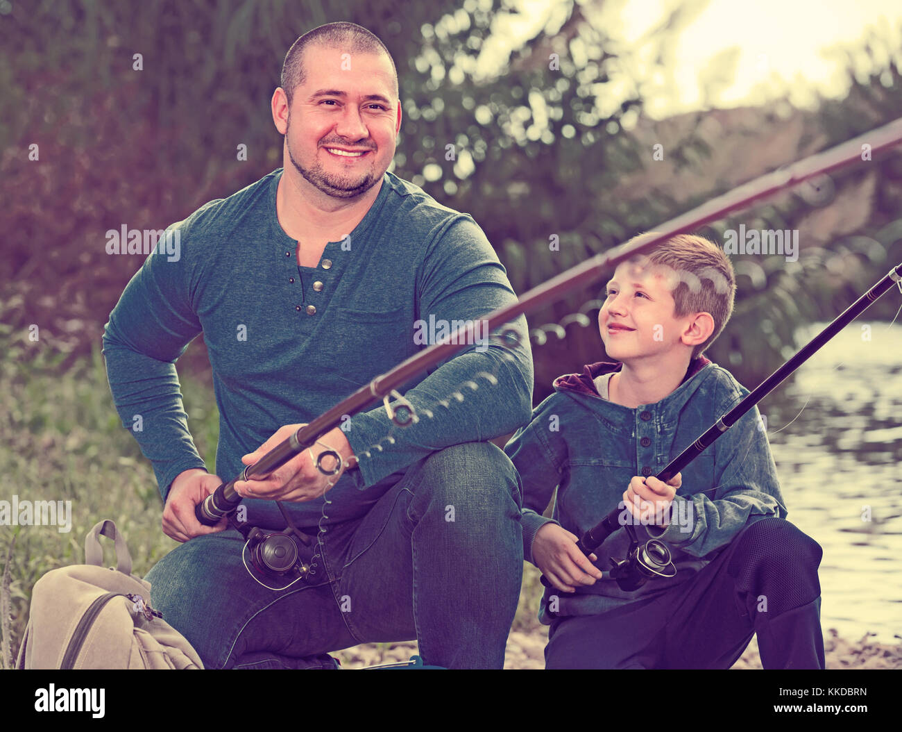 Fröhlich lächelnd vater und Teenager Sohn Fischen zusammen, die in den wilden Fluss. Im ...