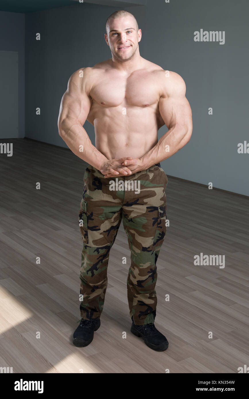 Hübscher junger Mann standhaft In Armee-Hosen und biegen Muskeln ...