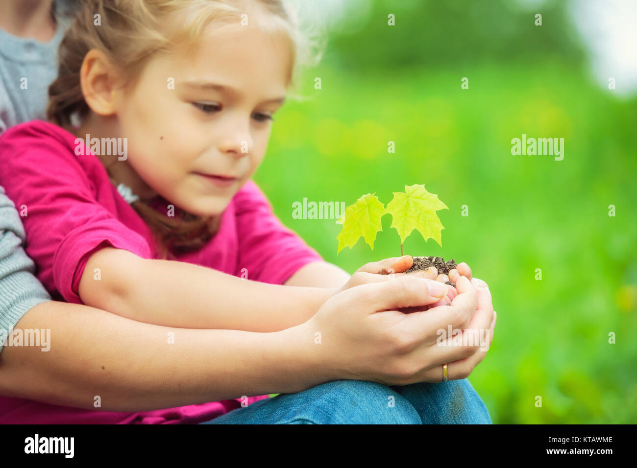 Erwachsene und Kinder, die kleine grüne Pflanze in den Händen halten ... Erwachsene und Kinder, die kleine grüne Pflanze in den Händen halten ...