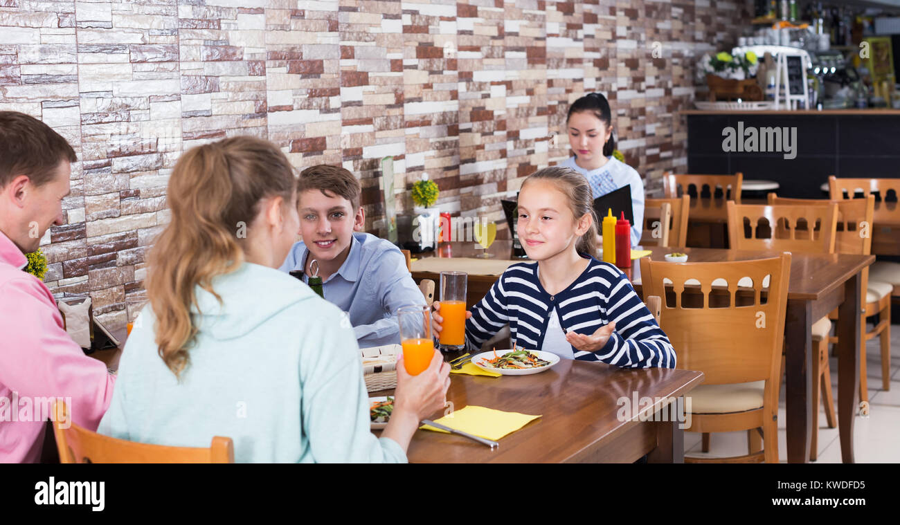 Froh, dass Eltern mit Kindern in Gespräch am Esstisch im Cafe ...