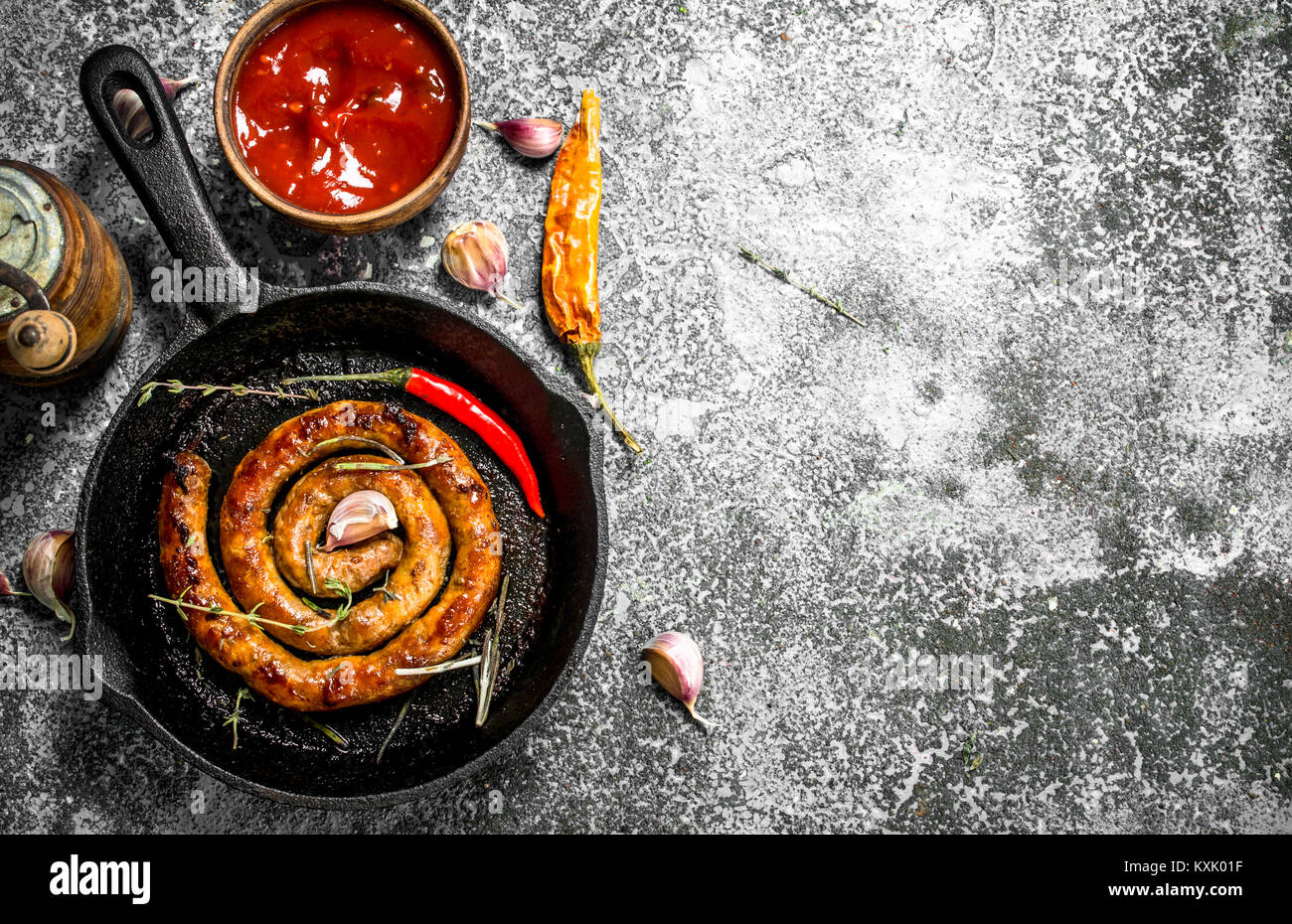 Wurst in einer Pfanne mit Peperoni, Knoblauch und Soße. Auf einem ...