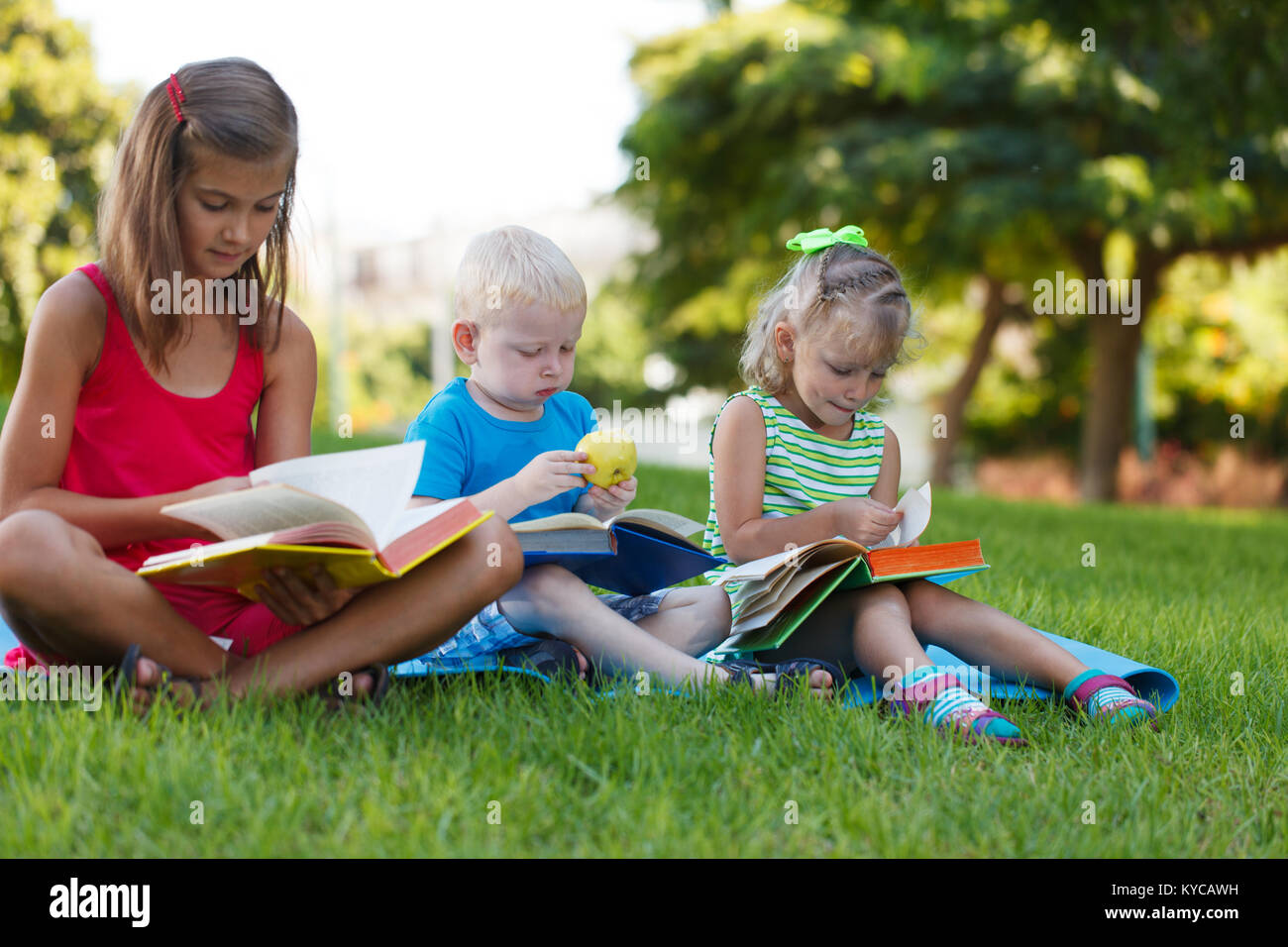 Drei Kinder auf der Wiese lesen Stockfotografie - Alamy
