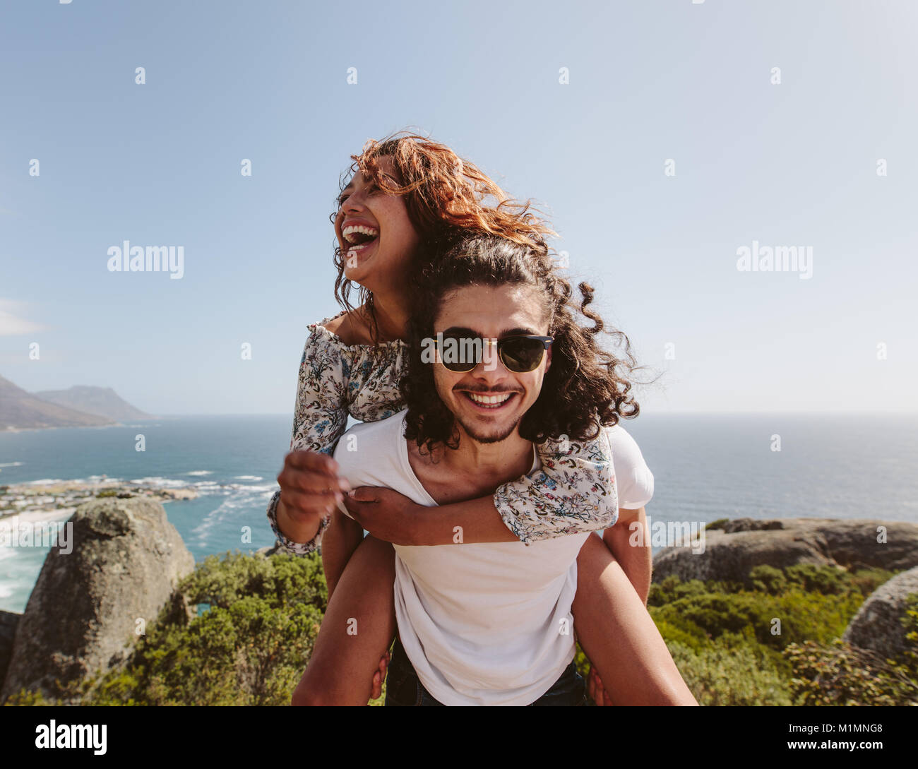 Lächelnder Mann, der piggyback Ride zu seiner Freundin auf der Spitze ...