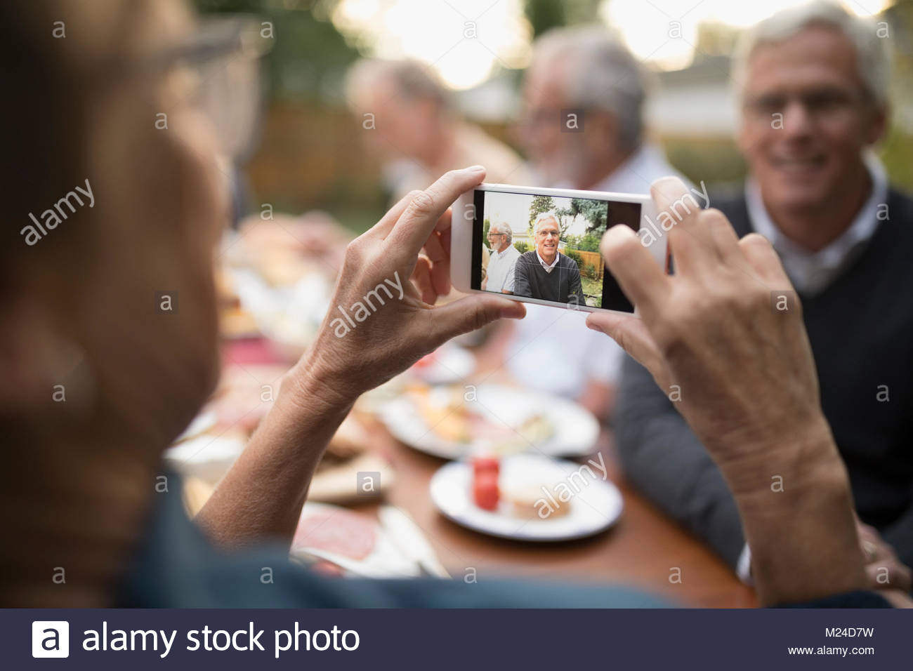 Ältere Frau fotografieren Mann mit Kamera Handy am Tisch ...