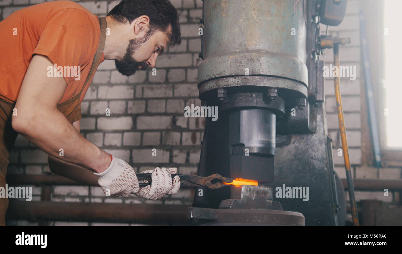 Man Schmied schmiedet das Metall an der mechanischen Hammer ...