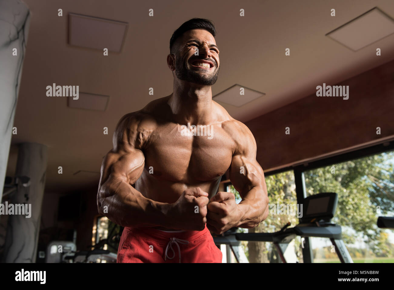 Gesunde junge Mann standhaft In der Turnhalle und biegen Muskeln ...