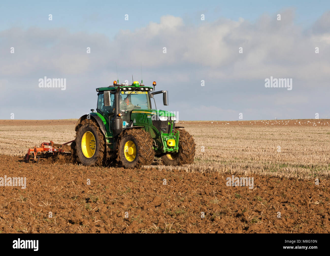 Ein Bauer mit einem Traktor eines gepflügten Feldes zu pflegen ...