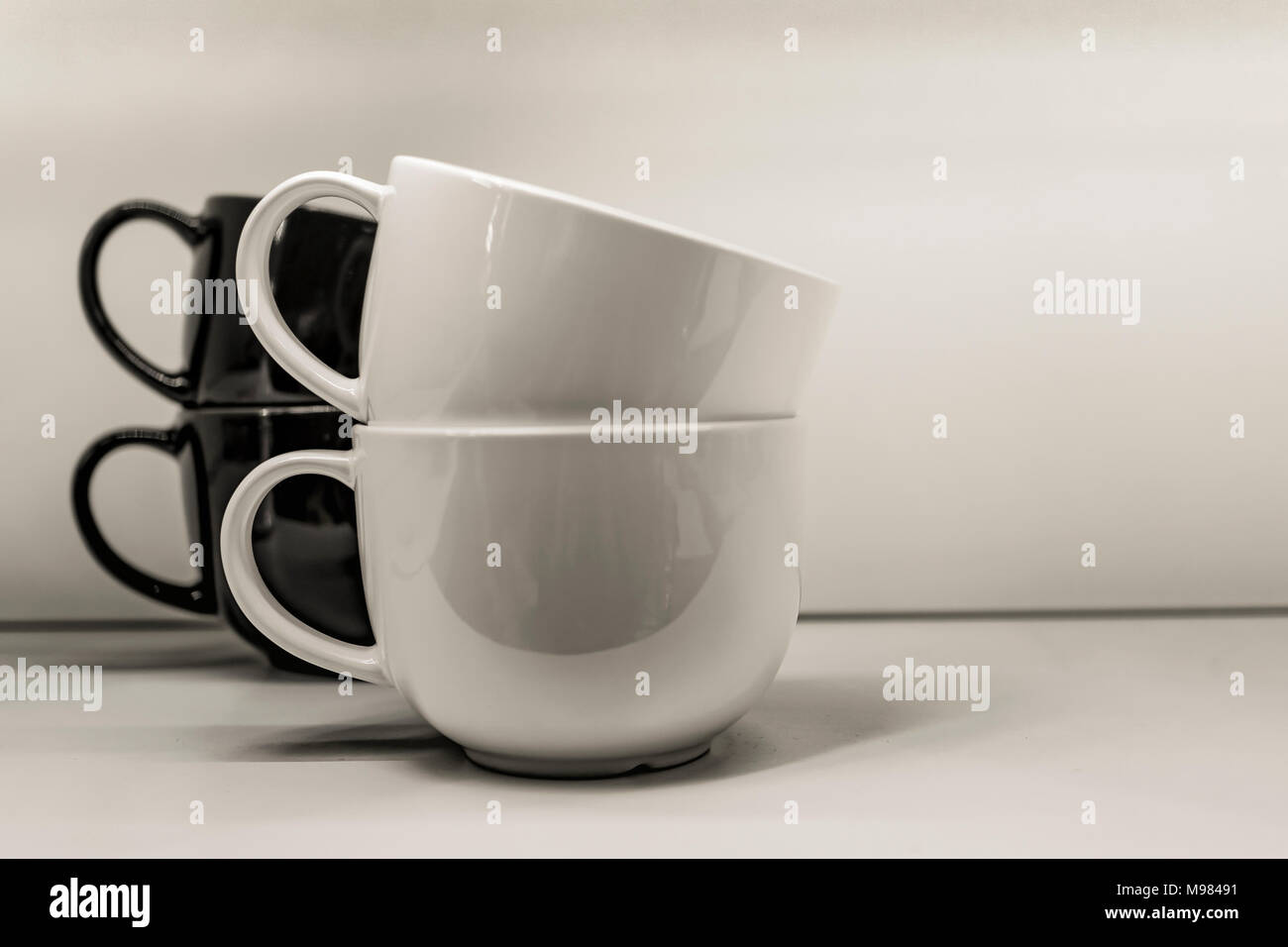 Zwei Tassen auf einem weißen Hintergrund stehen. Ein schwarzer und ...