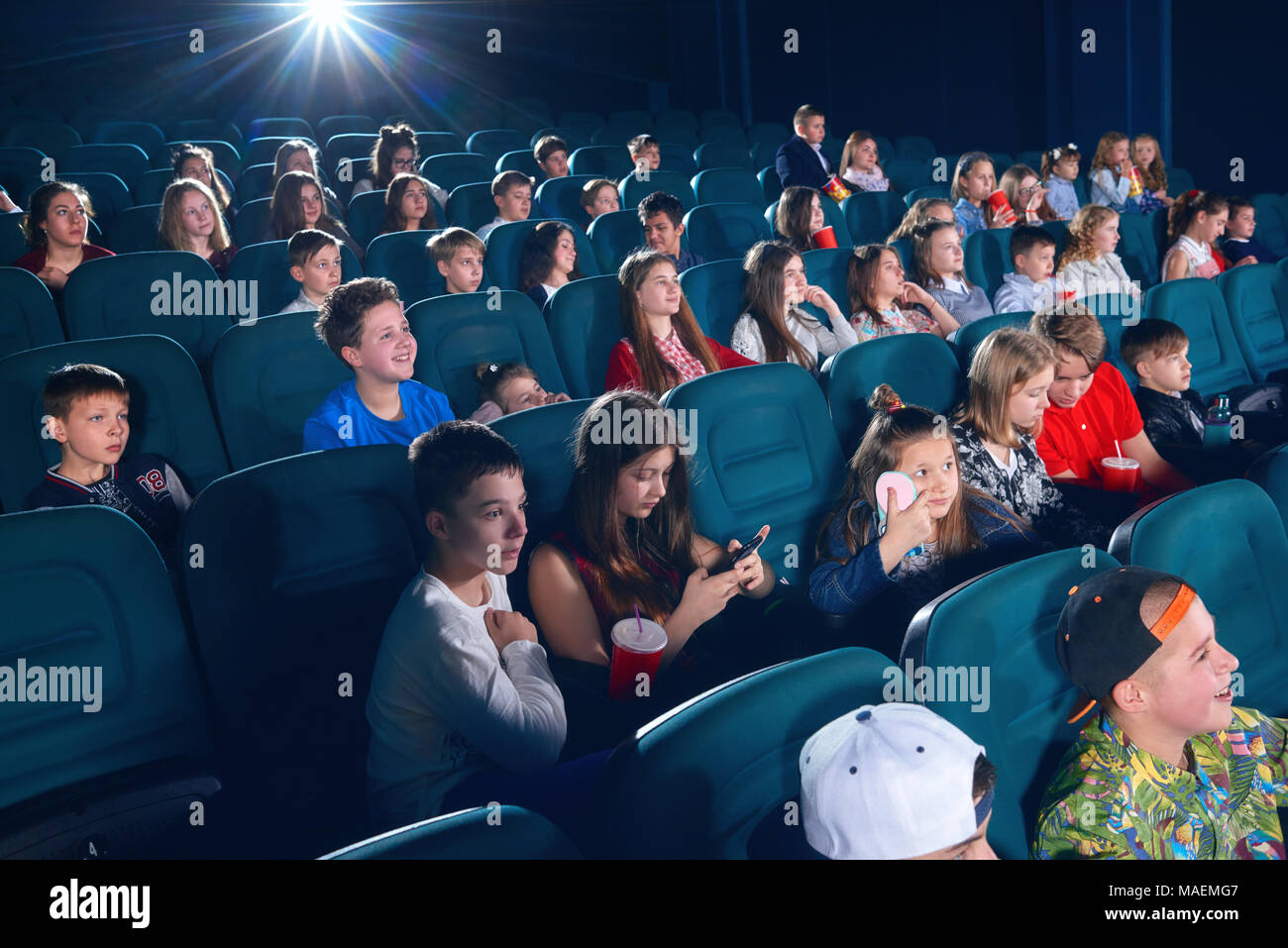 Mitschüler aufpassen Film im Kino. Die Jungen und Mädchen auf der Suche glücklich, emotional ...