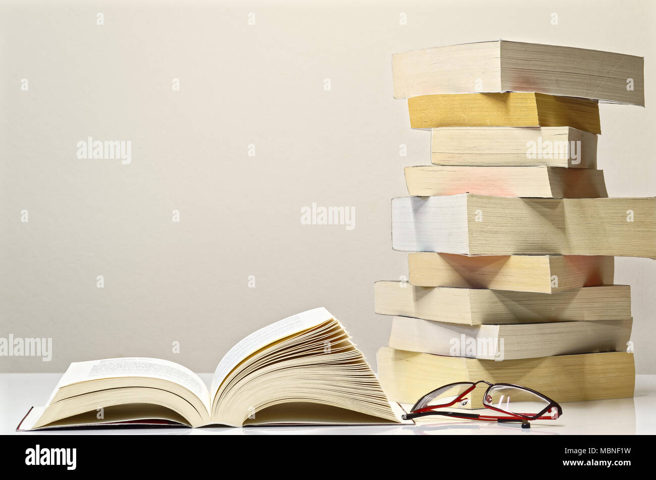 Buch, Brille und Stapel Bücher auf dem weißen Tisch Öffnen mit ...