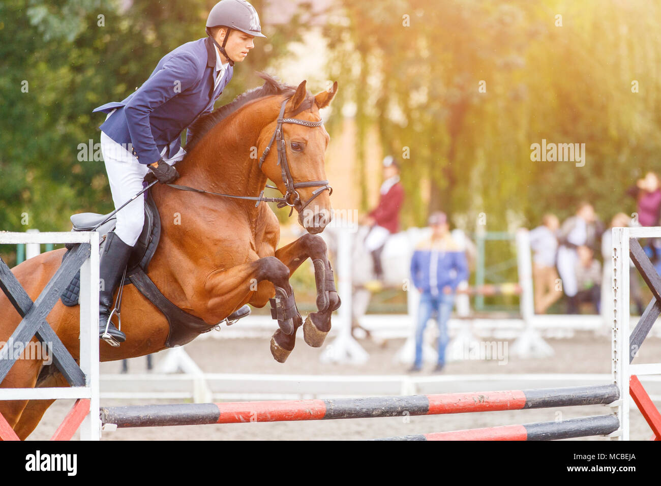 Junge Reiter Mann springen auf Pferd über Hindernis auf Reitturnier ...