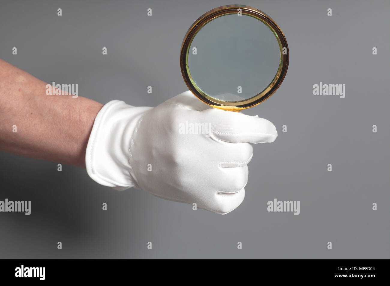 Männer Hand in weißen Handschuhen und goldene Lupe auf Grau ...