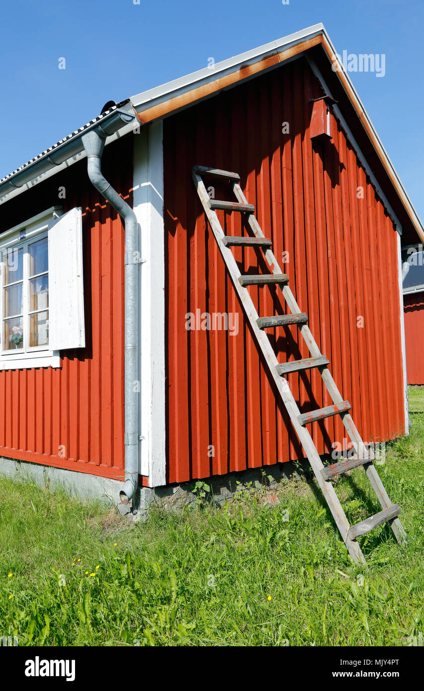 Eine Leiter an die Wand gelehnt auf einem rot lackierten kleinen ...