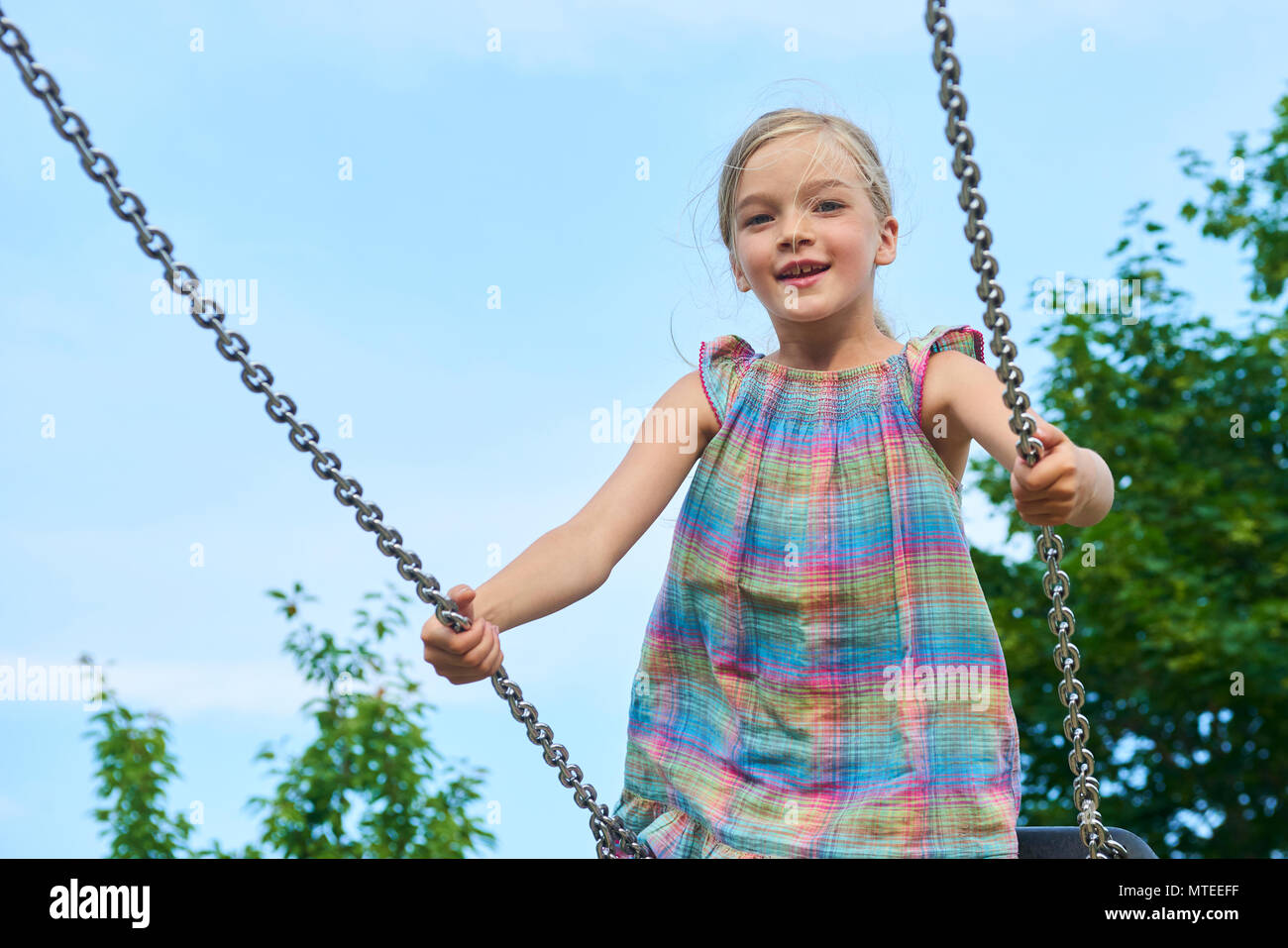 Kleines Kind blondes Mädchen Spaß haben auf einer Schaukel im Freien. Sommer Spielplatz. Mädchen ...