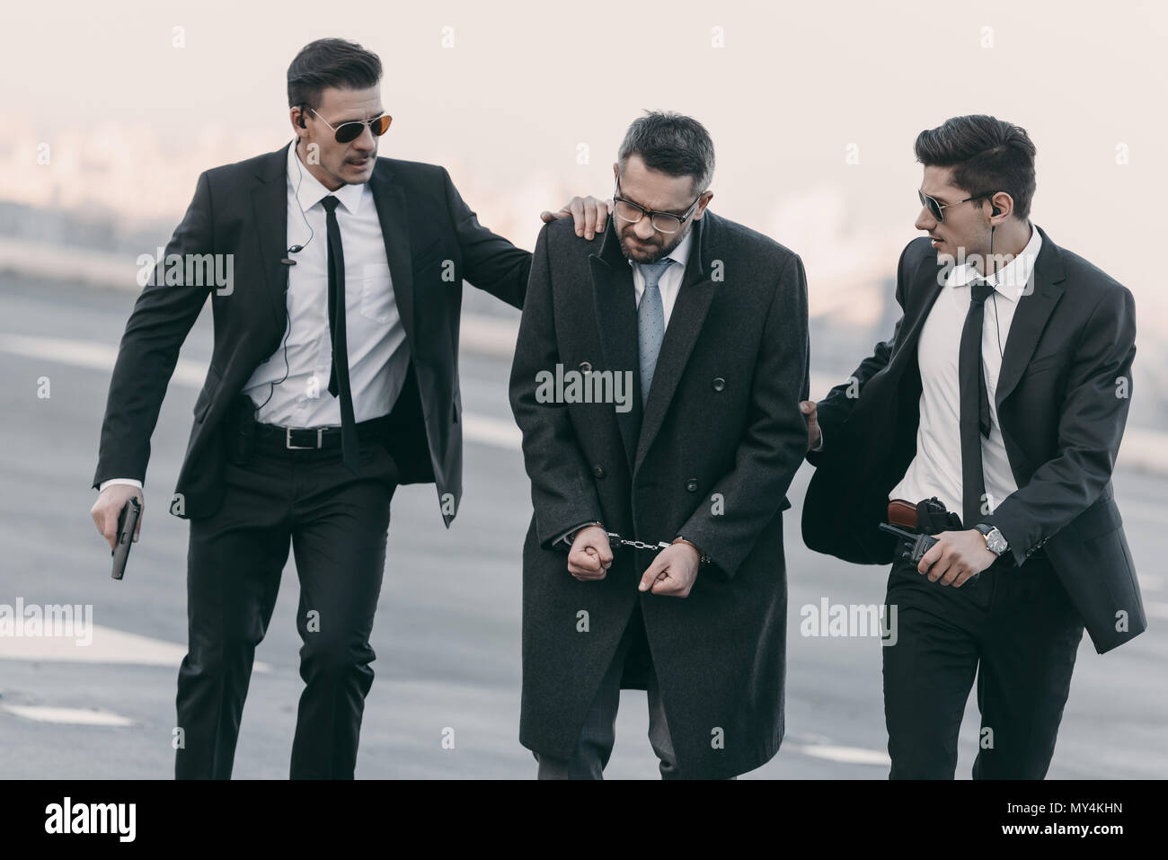 Security Guards mit Waffe mit verhaftet Mann in Handschellen auf ...