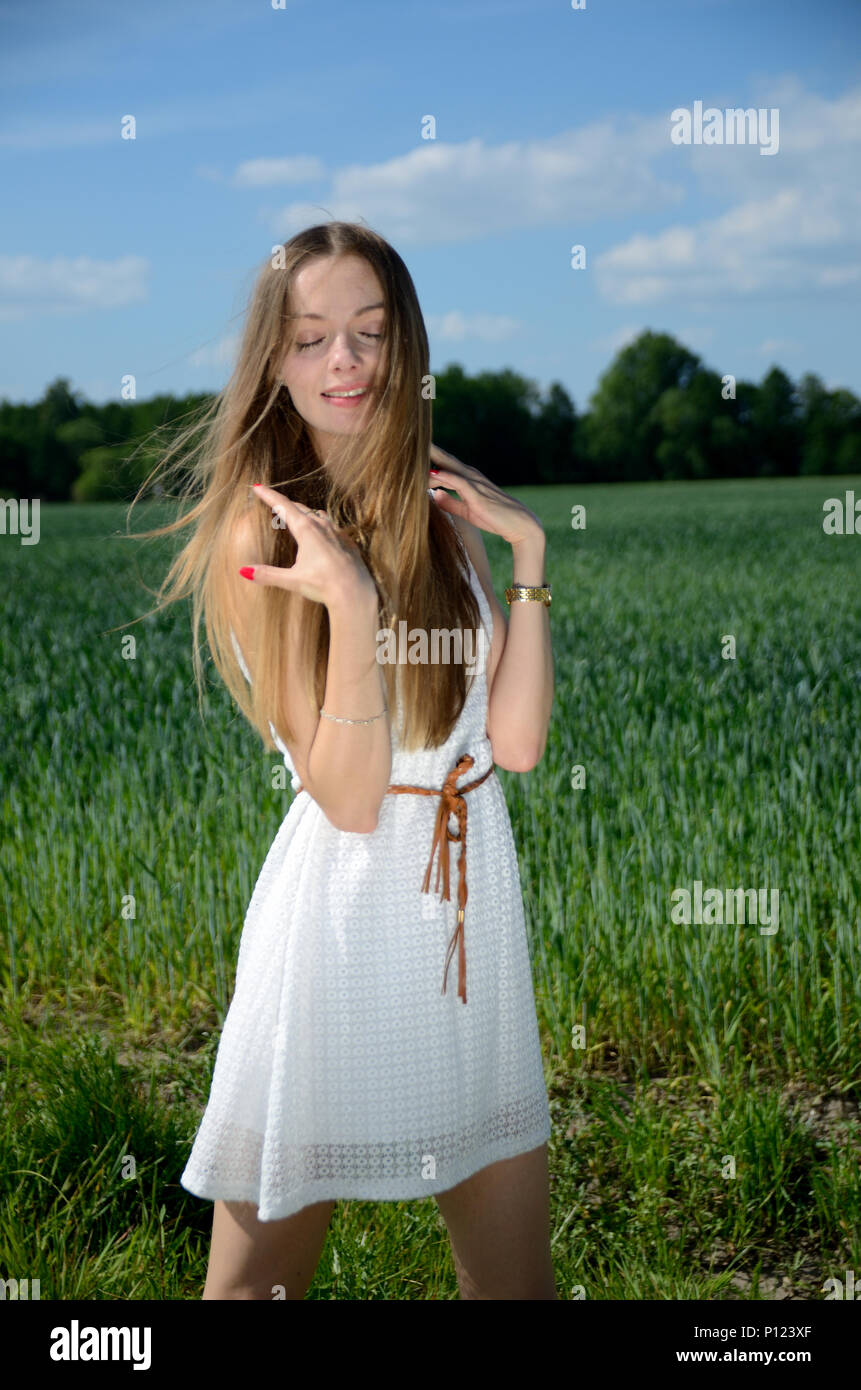 Zierliche Frau zu Fuß in das Feld Struktur, bekleidet mit weißen Kleid ...