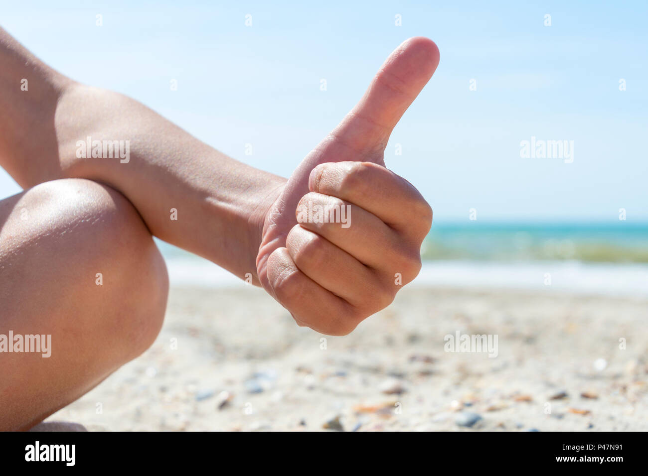 Nahaufnahme der Hand des Kindes am Strand gegen blaue Meer mit Wellen ...