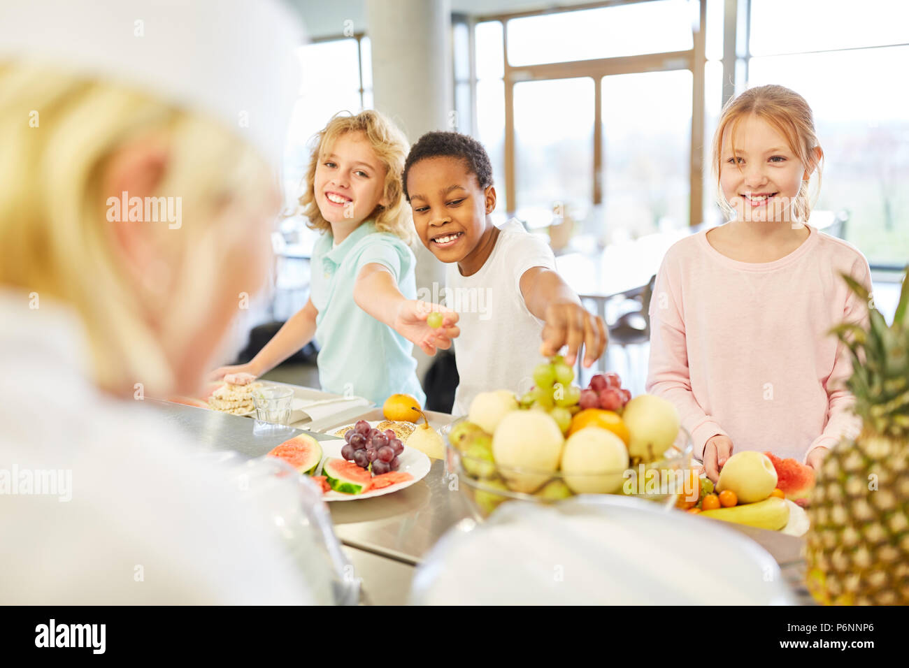 Gruppe der multikulturellen Kinder im Obst Buffet in der Cafeteria in ...