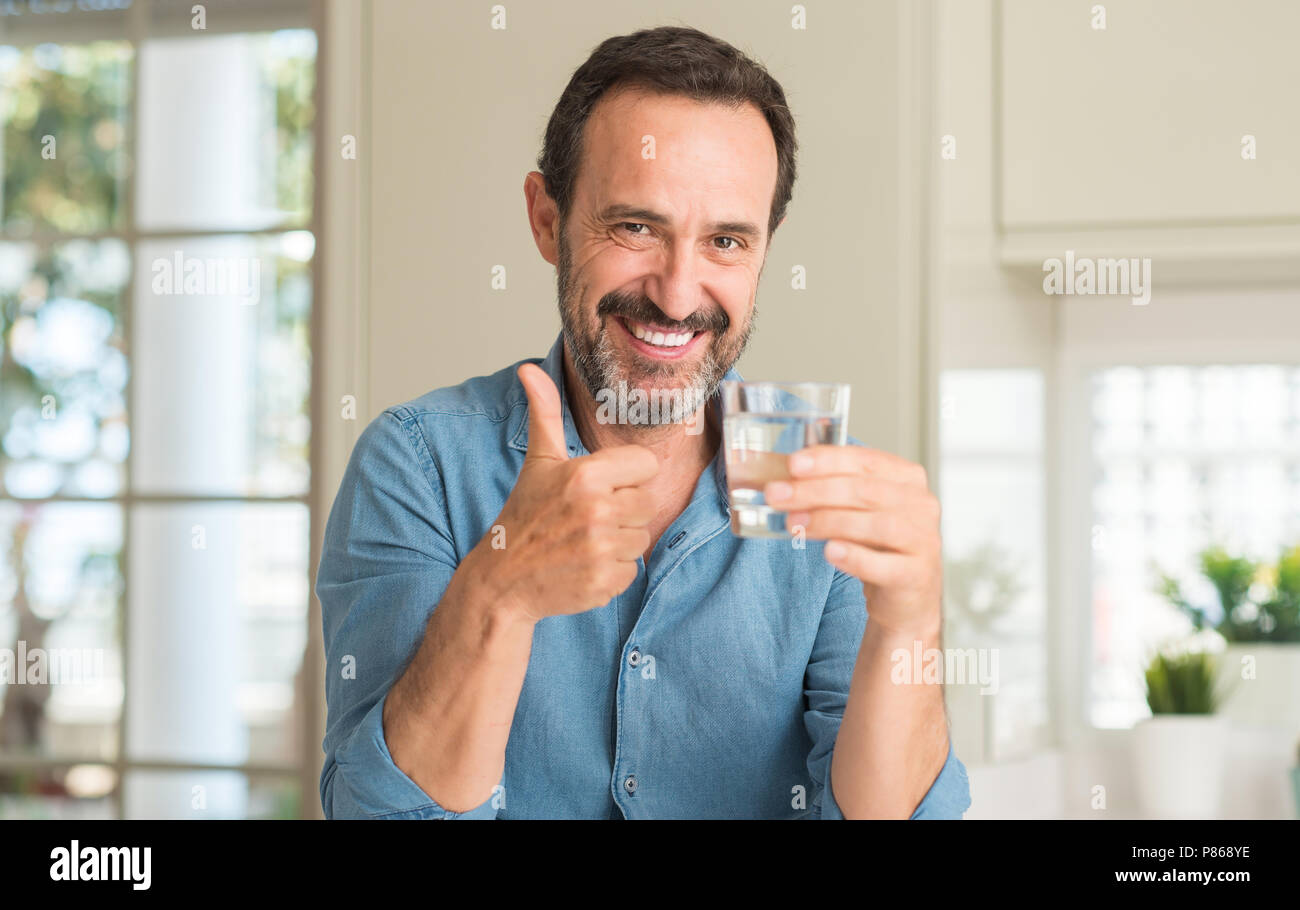 Mittleres Alter Mann trinkt ein Glas Wasser mit großen Lächeln tun ok ...