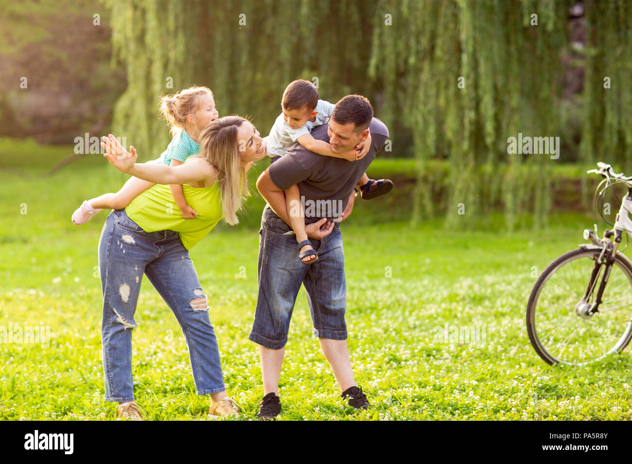 Familie Huckepack - lächelnde junge Eltern spielen mit ihren Kindern in ...