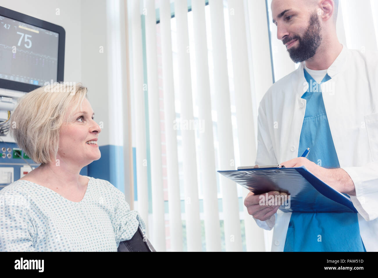 Arzt im Gespräch mit Patienten im Aufwachraum der Klinik ...