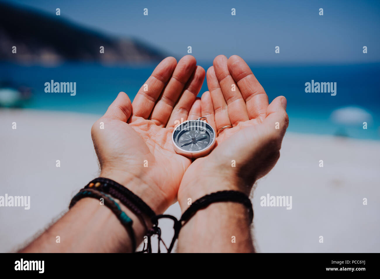 Hand Palmen mit Metall Kompass auf dem sandigen Strand geöffnet. Suchen ...