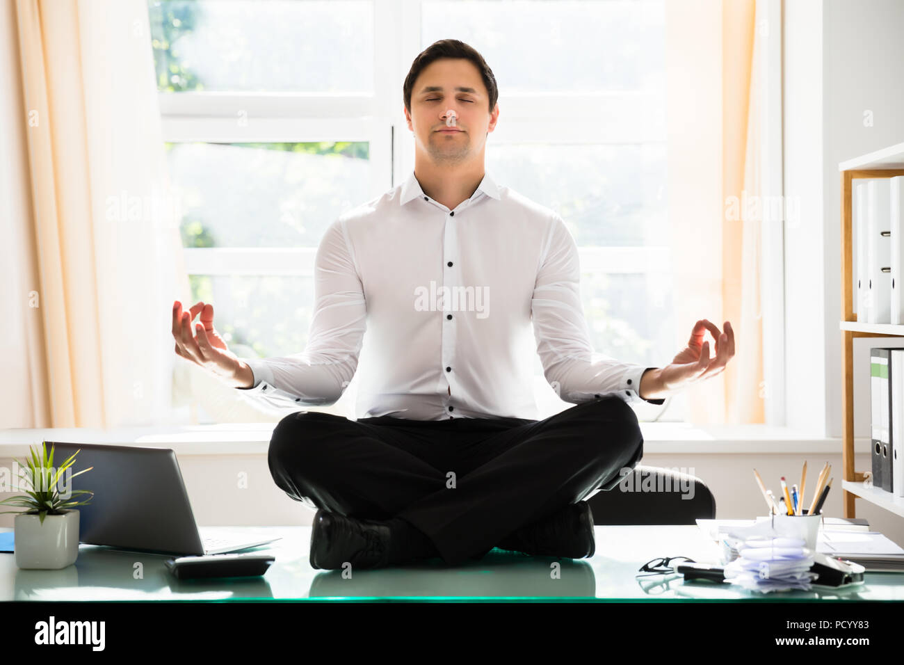 Entspannt junge Unternehmer der Meditation im Lotussitz auf Glas ... Entspannt junge Unternehmer der Meditation im Lotussitz auf Glas ...