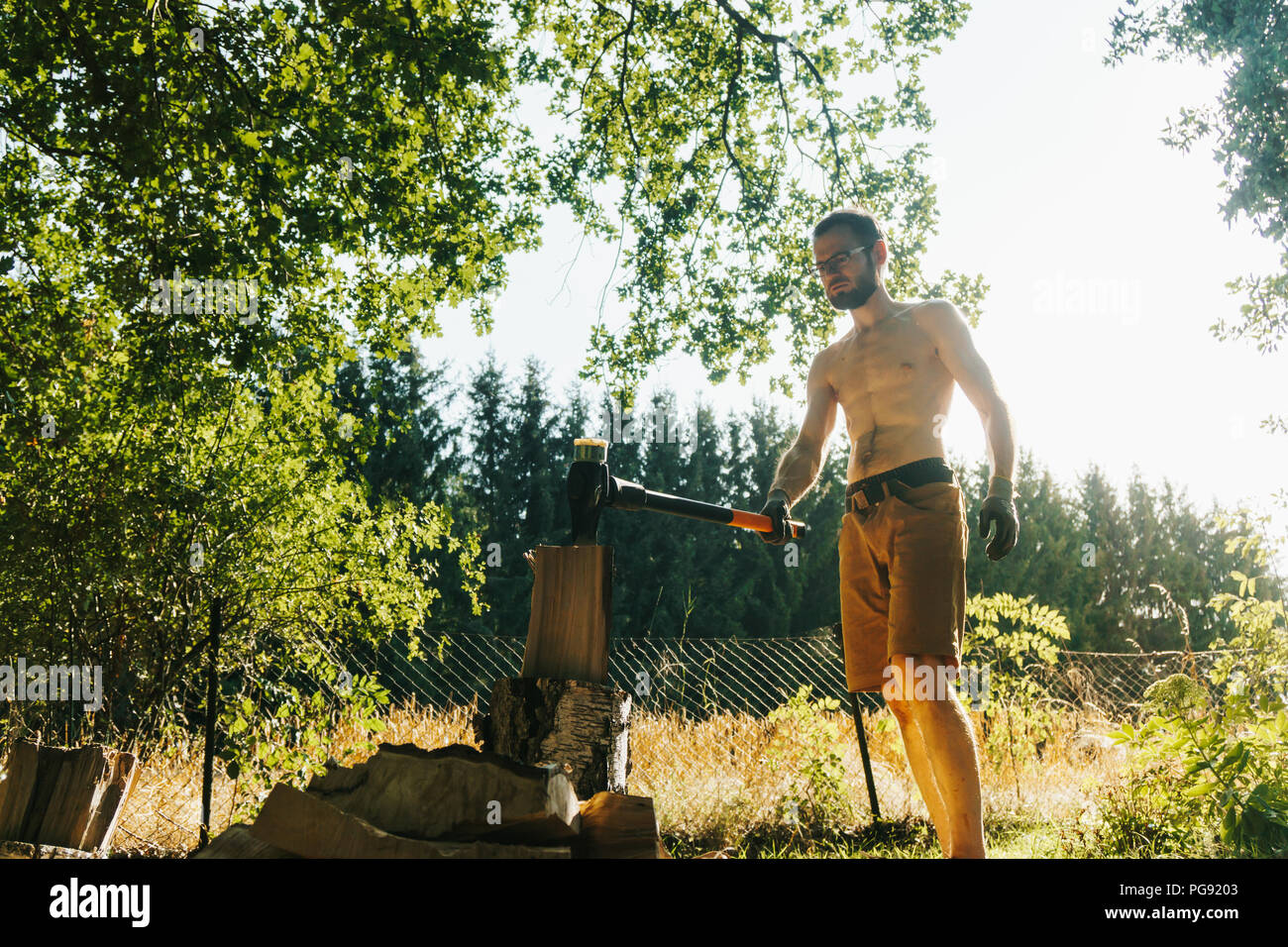 Bild von shirtless Mann, der Hacken ist Holz mit einer Axt ...