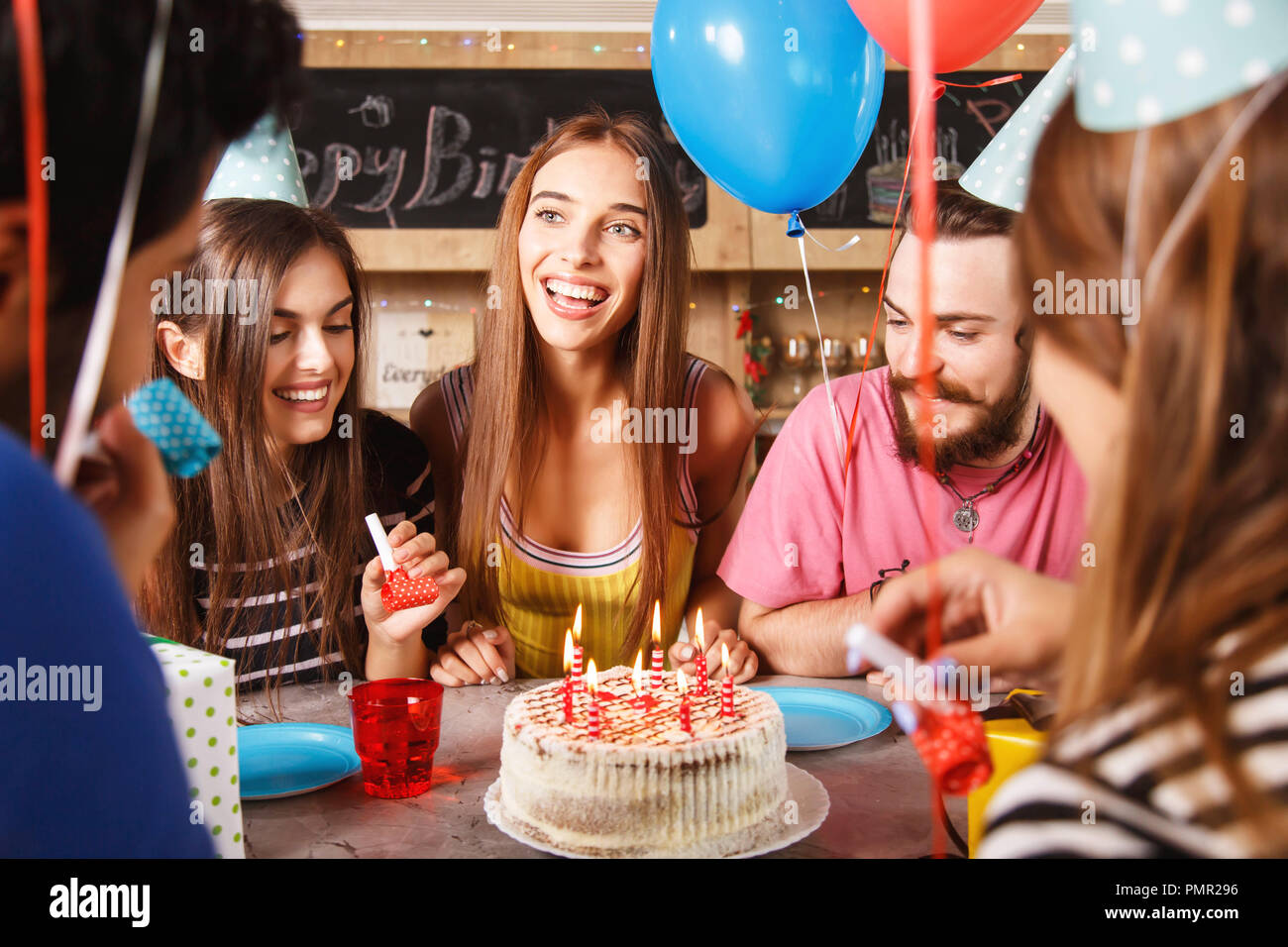 Fünf junge Erwachsene feiern eine Party, wie Sie sitzen um einen Tisch ...