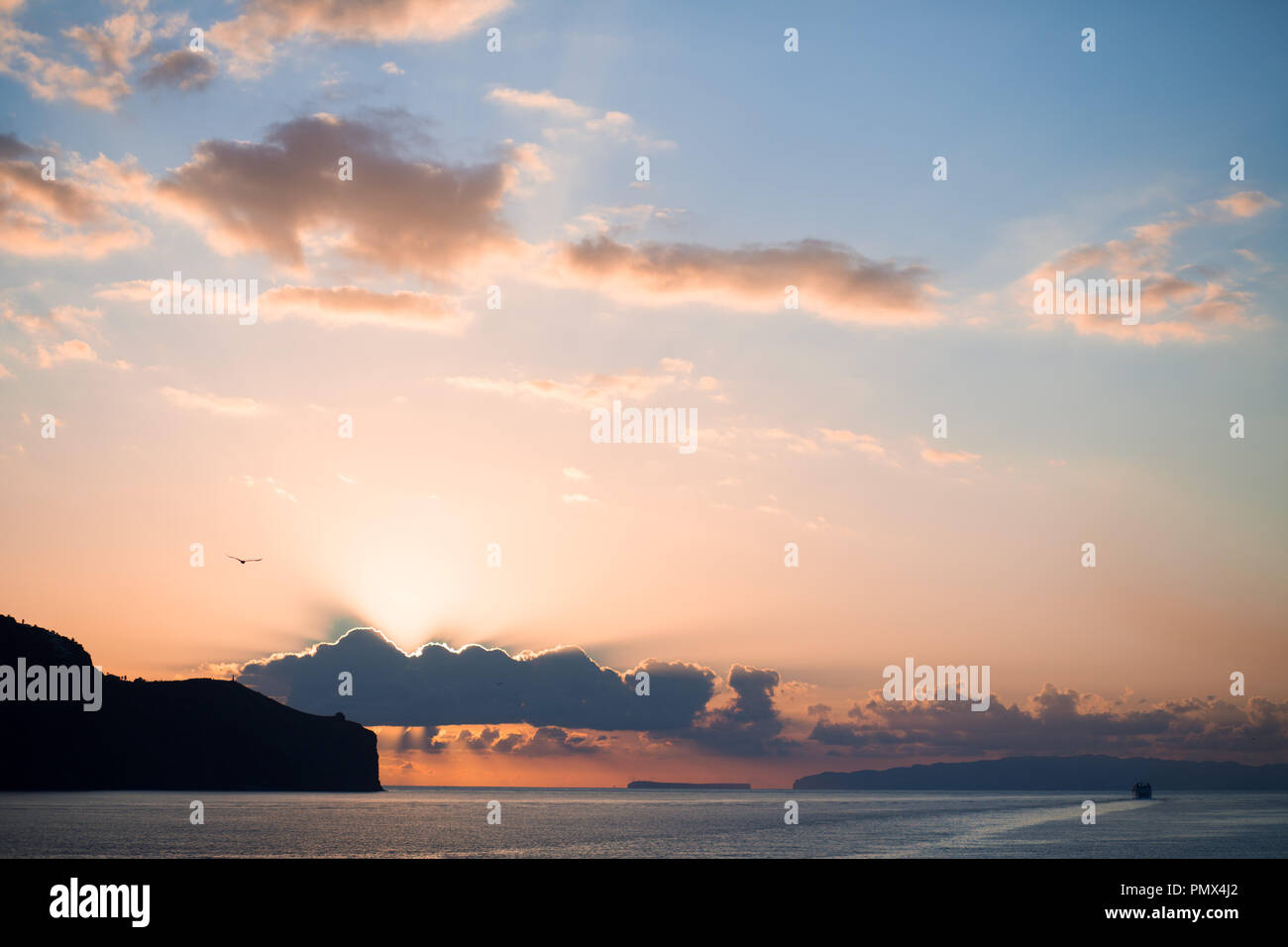 Sonnenstrahlen hinter einer Wolke über dem Meer / Ozean bei ...