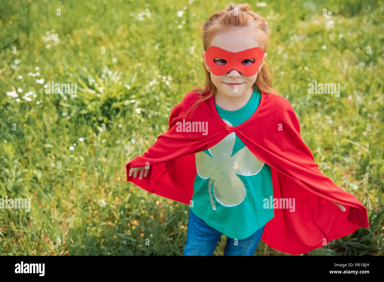 Niedliche Kind in roten Superhelden Maske und Cape stehen im Sommer ...